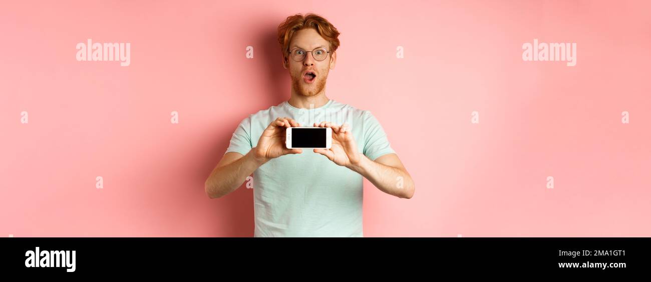 Amazed redhead man gasping and staring with awe at camera, showing ...