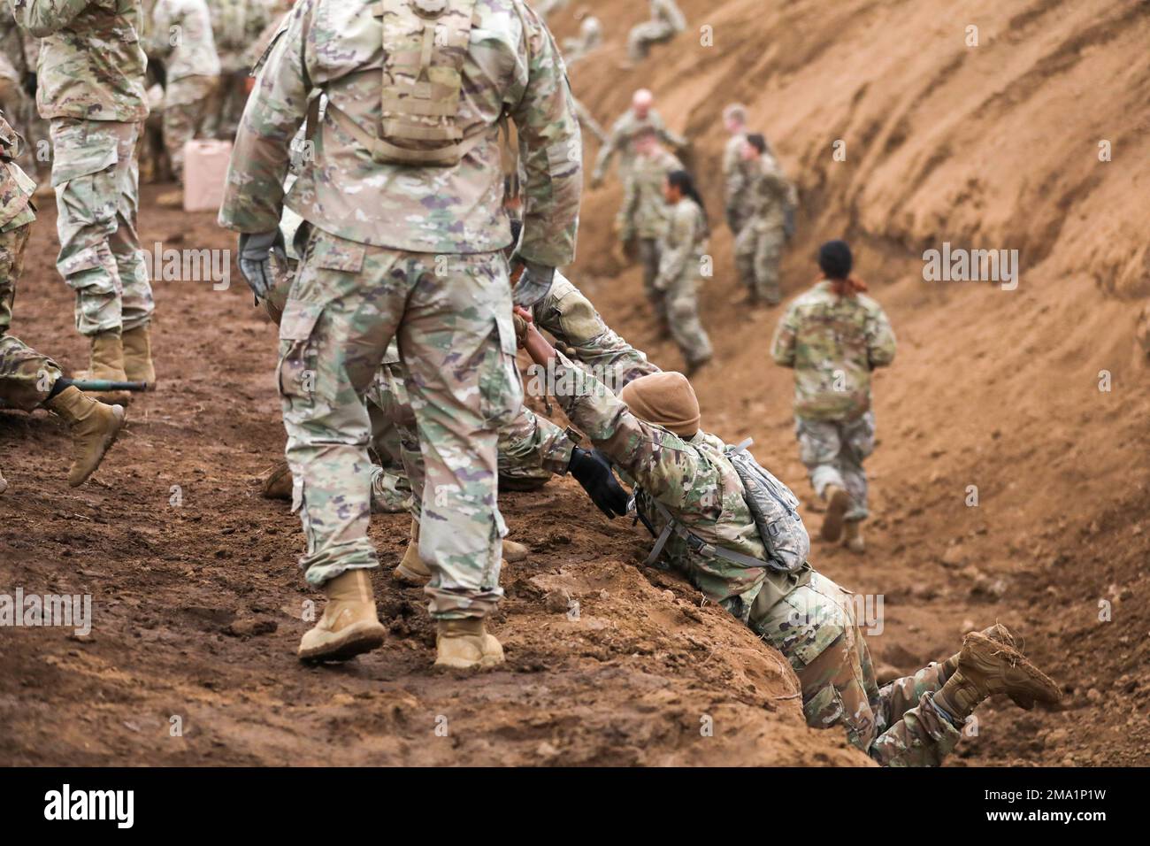 Soldiers help each other up a trench while competing in the 4th ...
