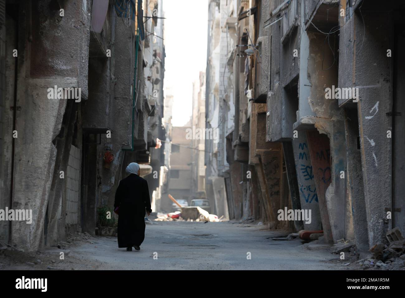 A woman walks through Yarmouk camp in Damascus Syria that has seen ...