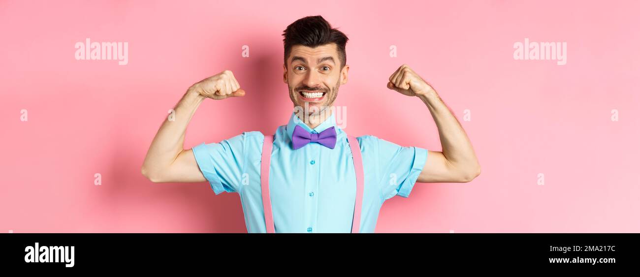 Smiling caucasian man with bow-tie and suspenders, showing muscles and ...