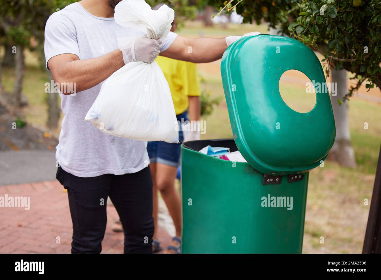Volunteer cleaning, trash bin and man throw garbage, pollution or waste ...
