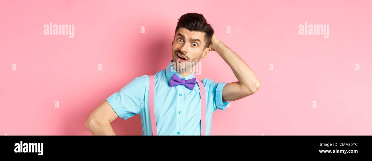 Confused funny man scratching head, staring puzzled at camera, know ...