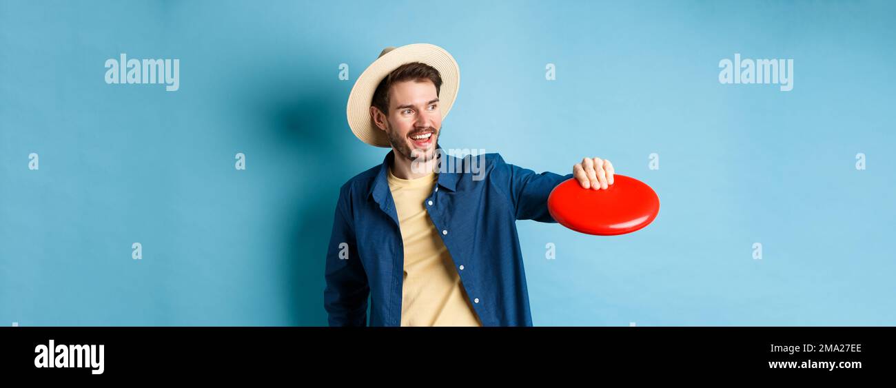 Happy smiling guy catching frisbee while playing with friends on summer ...
