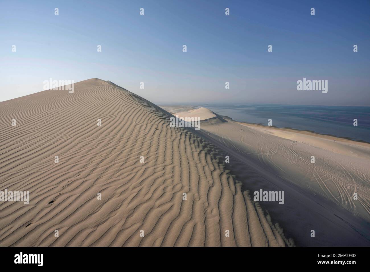 Sand dunes meet the Khor Al Adaid Inland Sea, on the border between ...