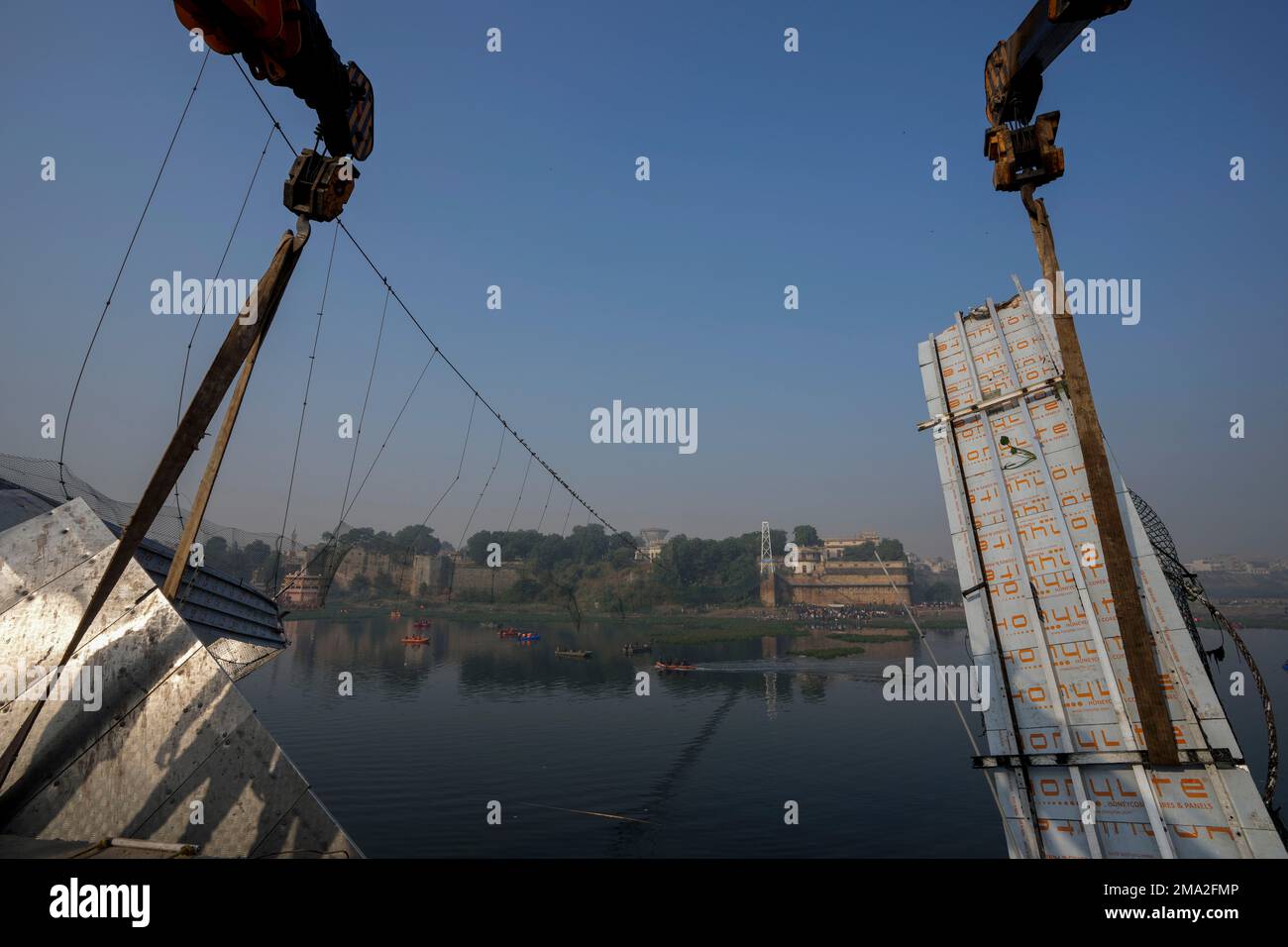 Workers use machinery to remove the debris of a pedestrian bridge that ...