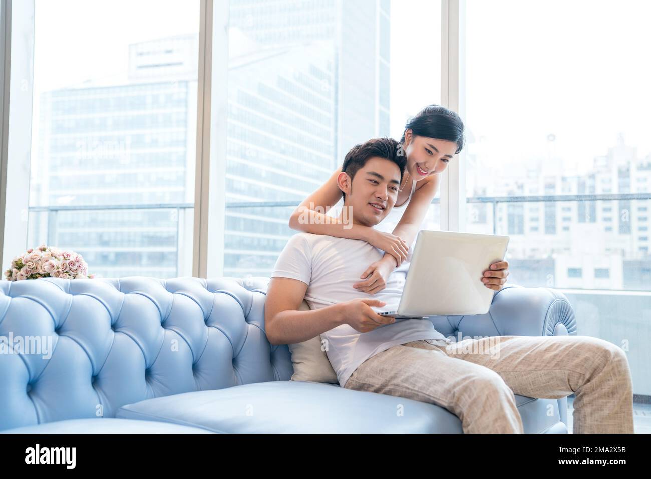 Young couples to use a computer on the sofa Stock Photo - Alamy