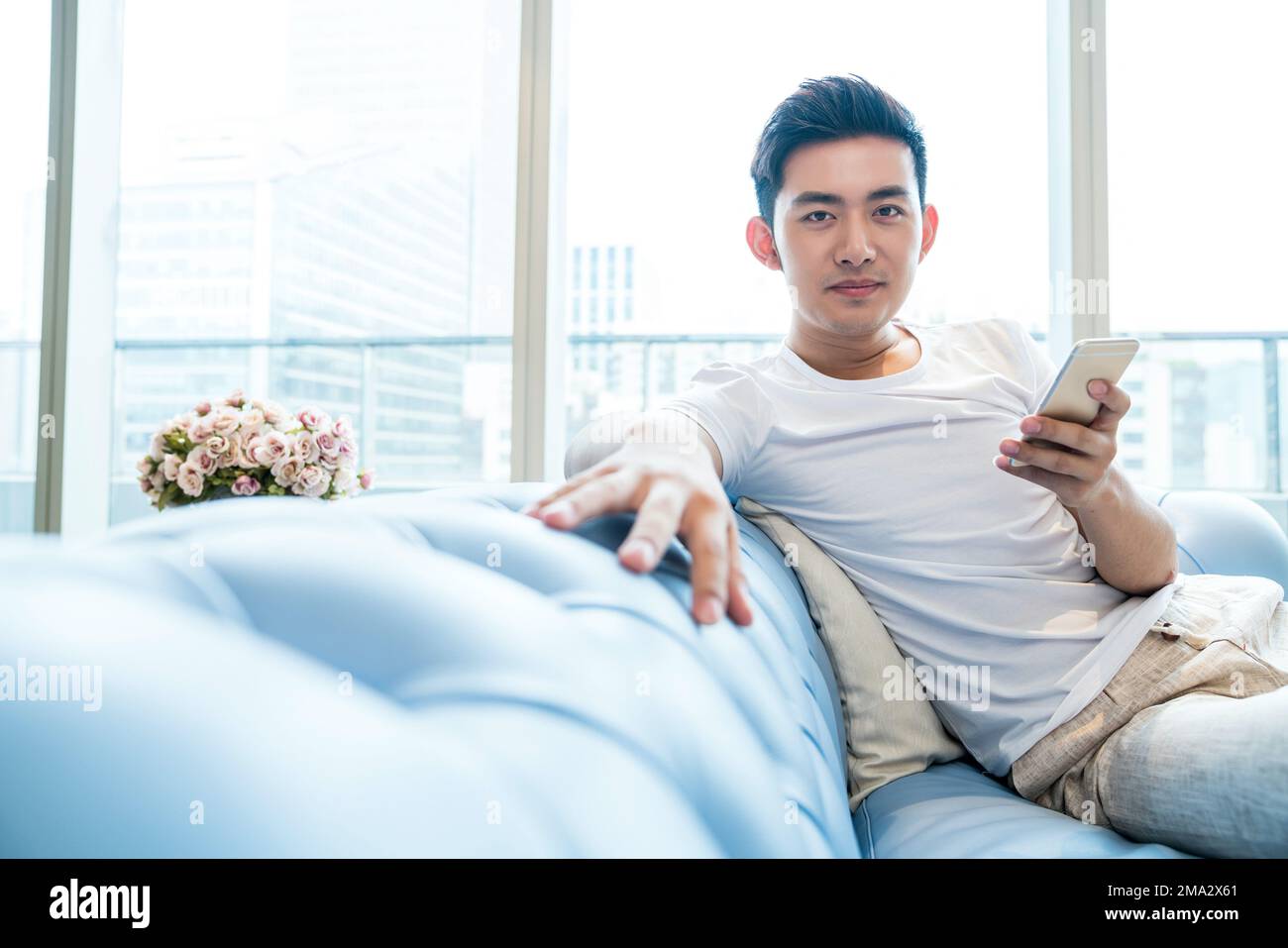The young man on the sofa and the use of mobile phones Stock Photo - Alamy