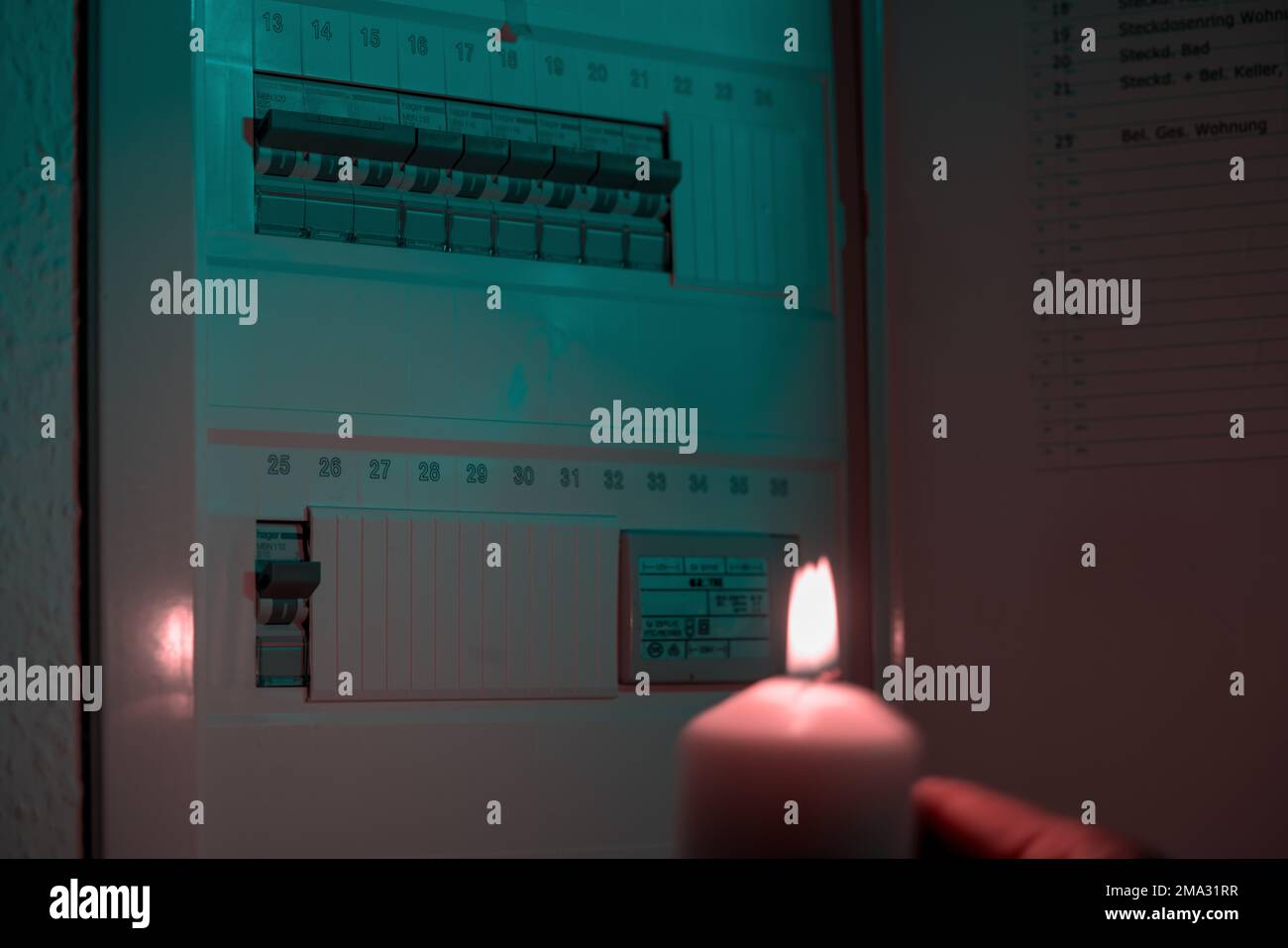 hand holding a candle near an electrical switchboard. Blackout concept ...