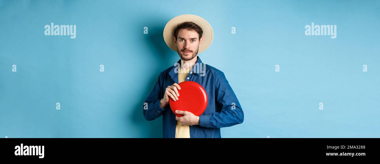 Young man throwing frisbee, playing on summer vacation, standing in ...