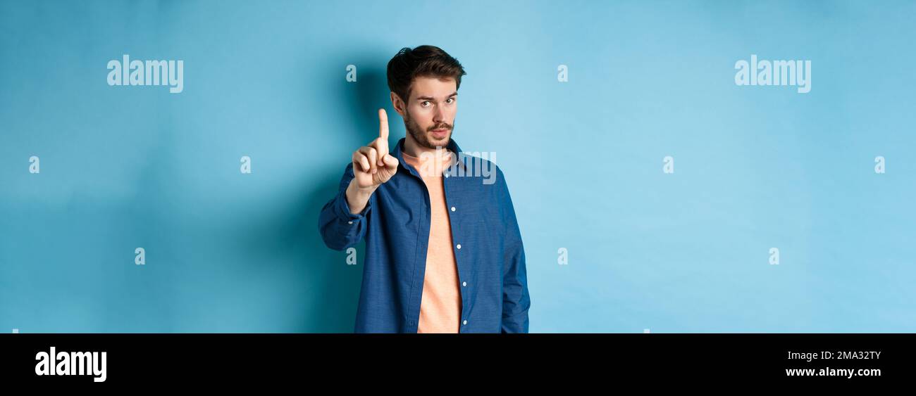Image of young man give warning, teaching a lesson, raising one finger ...