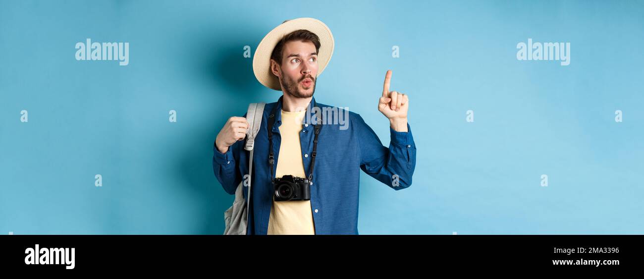 Handsome tourist looking curious and pointing up, showing interesting ...