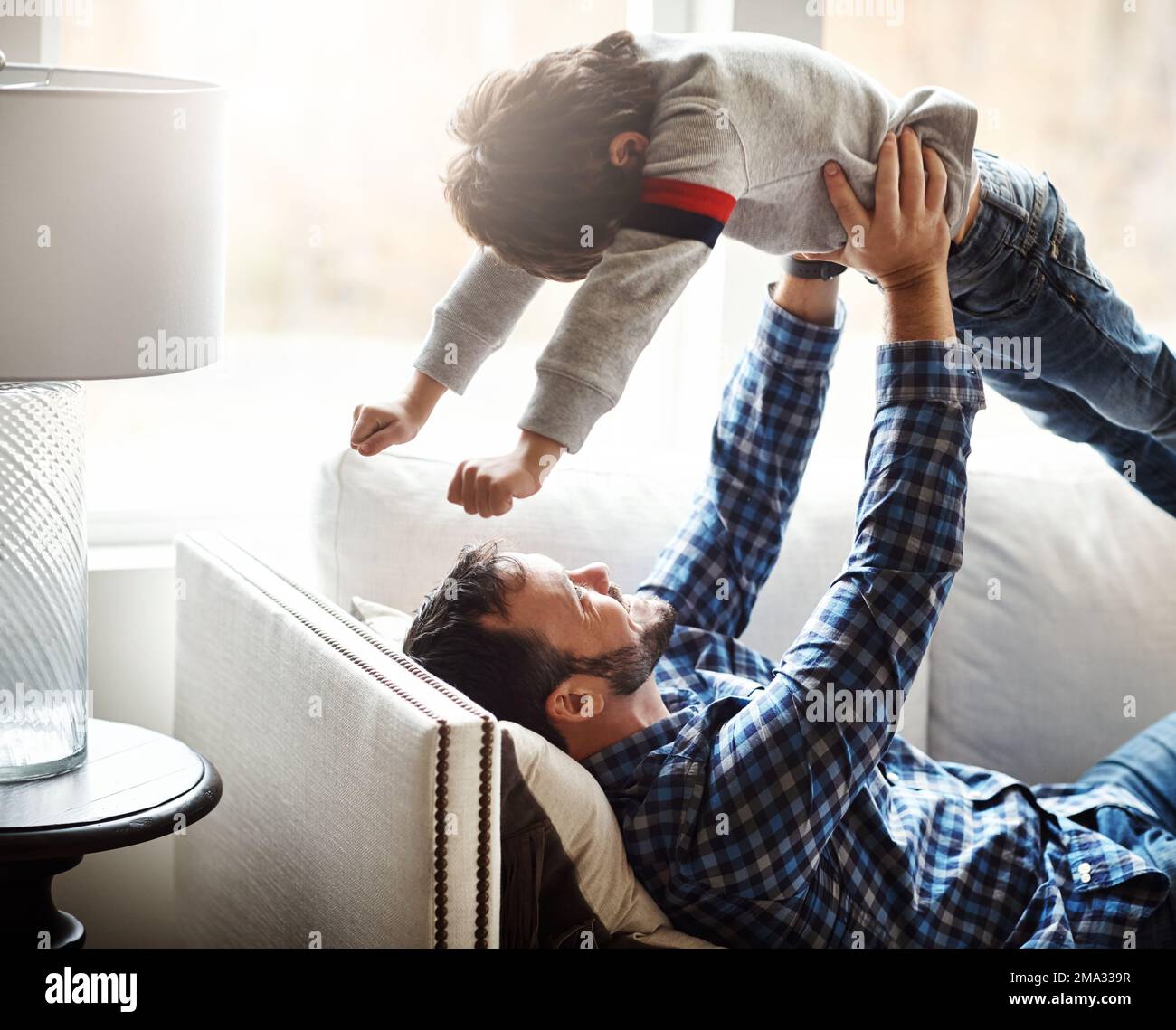 Happy, father and lifting kid on home sofa for bonding, wellness and ...