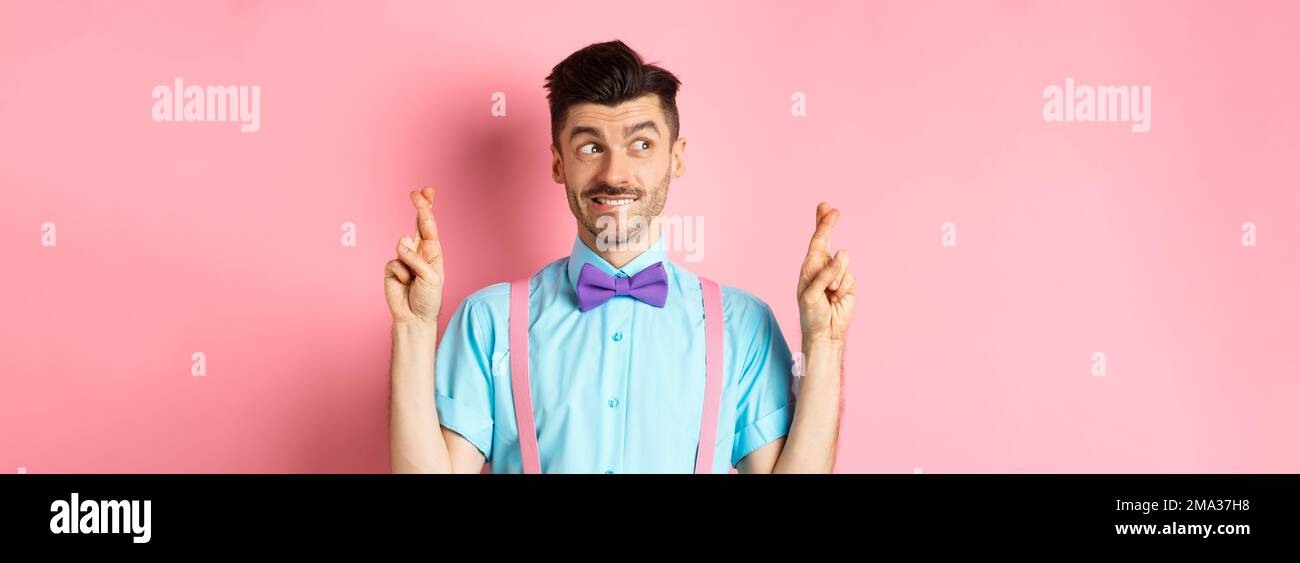 Hopeful handsome guy in bow-tie making wish, cross fingers for good ...