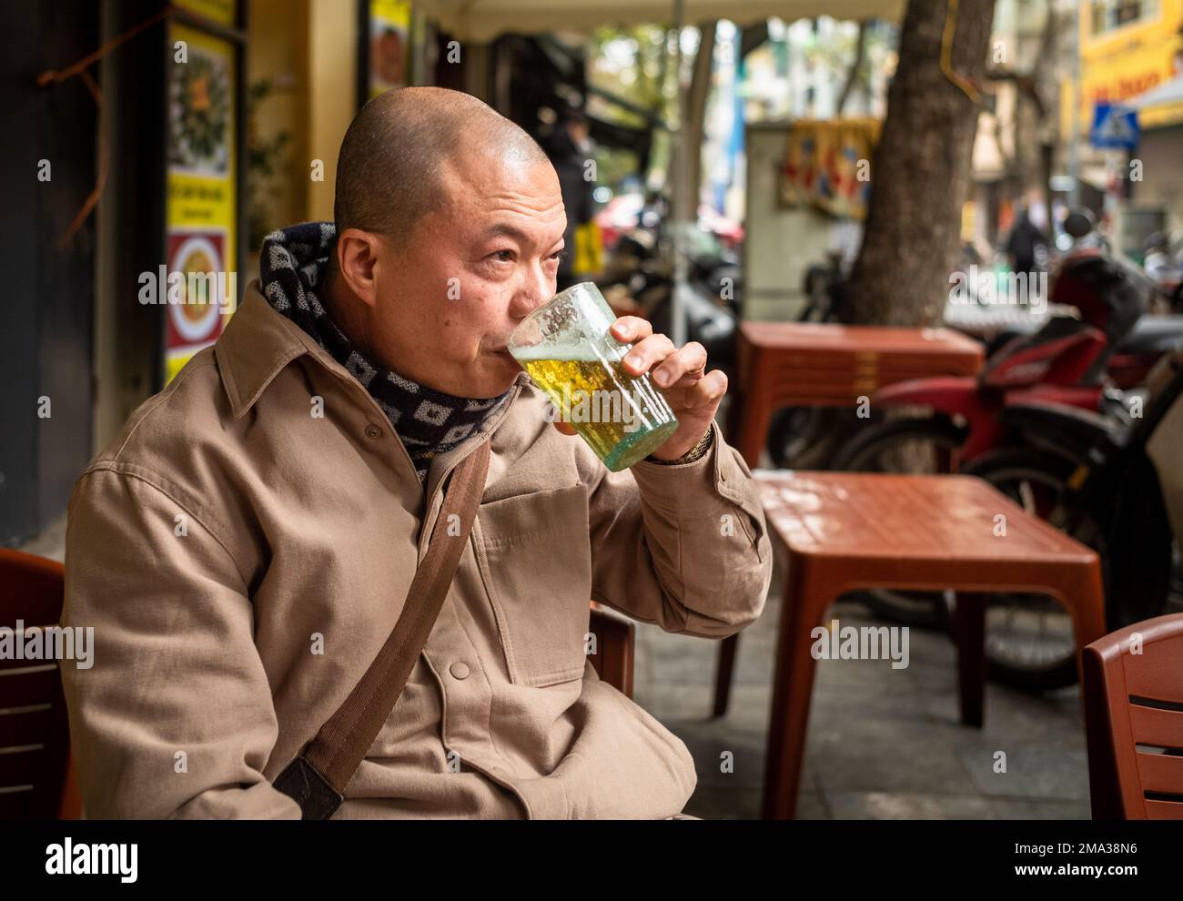 A Vietnamese man drinks a glass of bia hoi, or fresh beer, on the ...