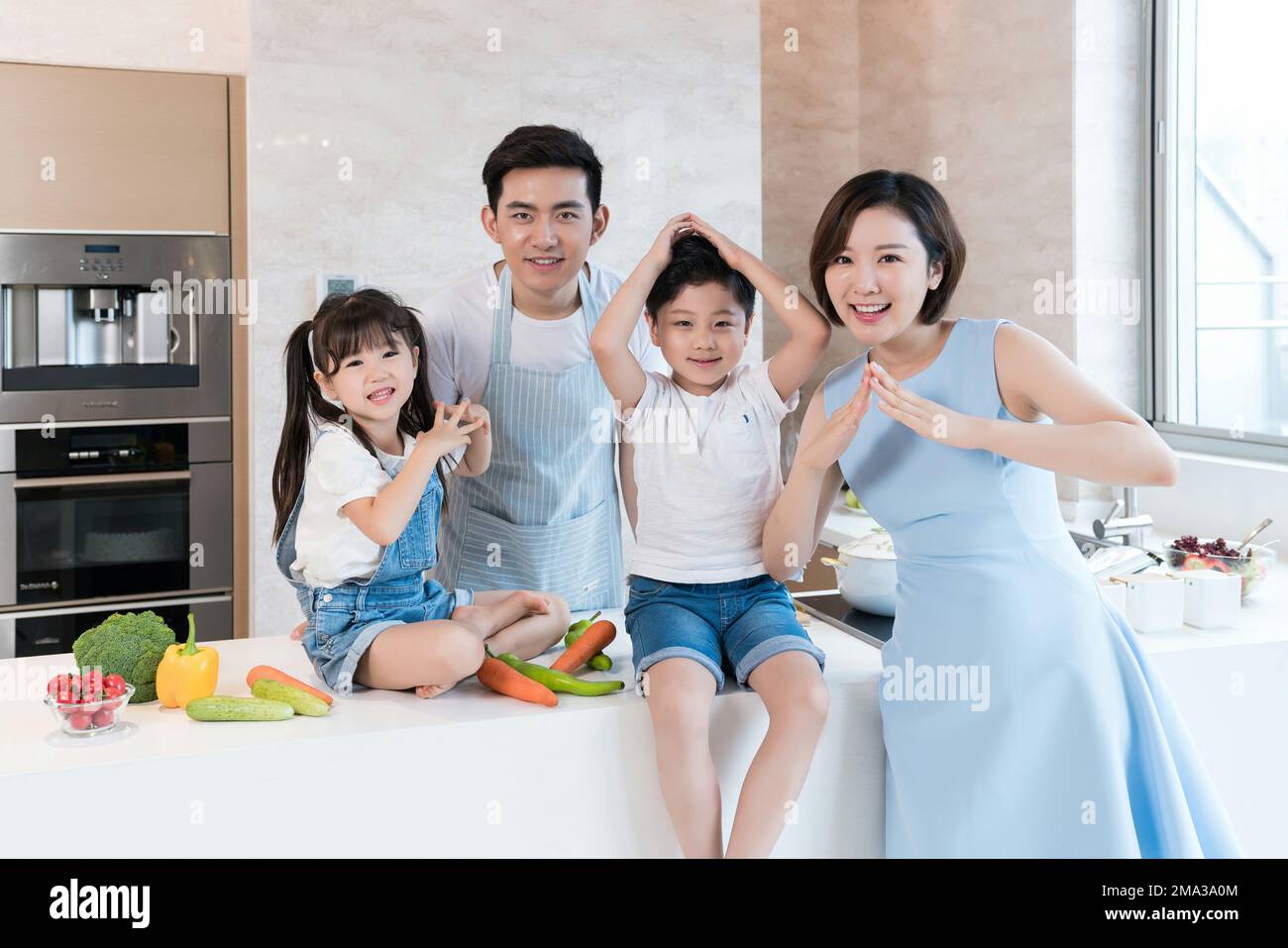 Happy family of four cooking in the kitchen Stock Photo - Alamy