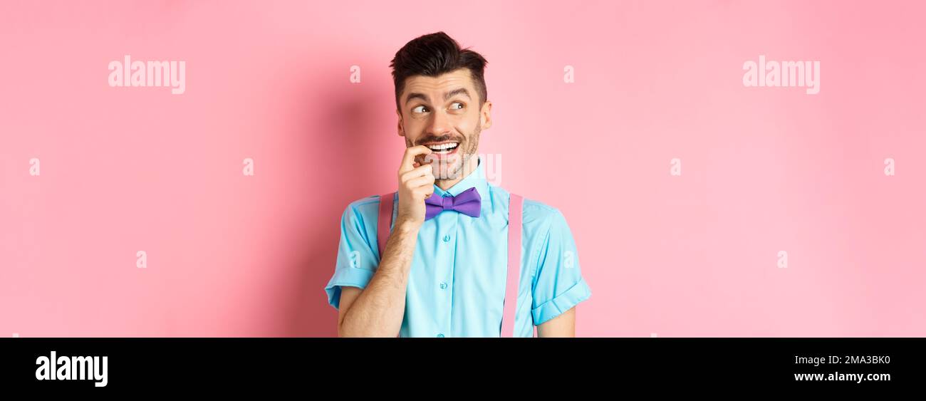 Image of smiling man making choice, looking dreamy and happy aside ...