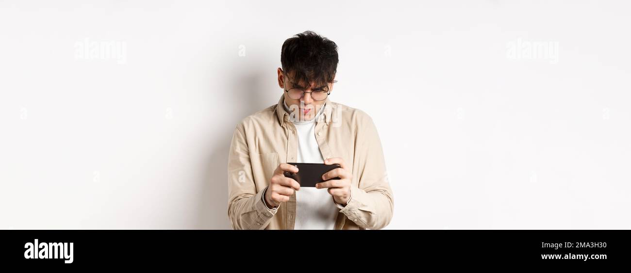 Handsome young man stare at mobile screen and playing video game on ...