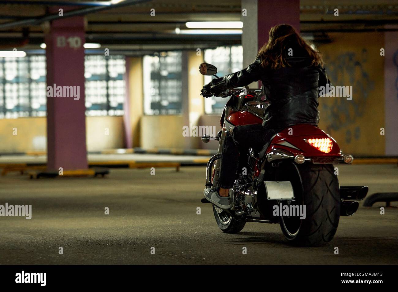A man on a motorcycle rides in an urban landscape among concrete ...