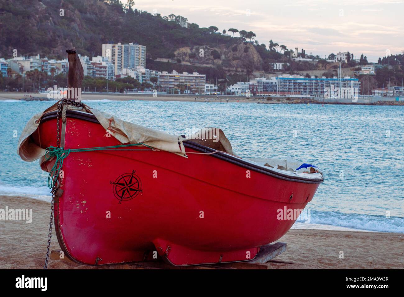 Lonely red fishing boat moored to the fine sand of the shore on the ...
