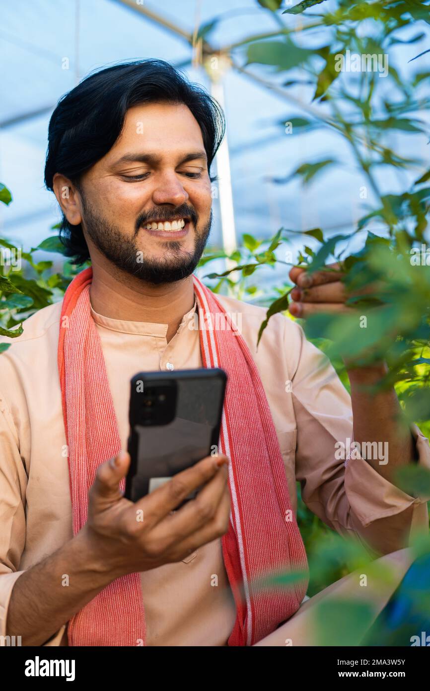 vertical shot young farmer checking growth of plants from mobile phone ...