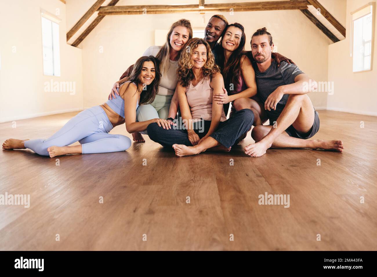 Portrait of people smiling at the camera while sitting on the floor in ...