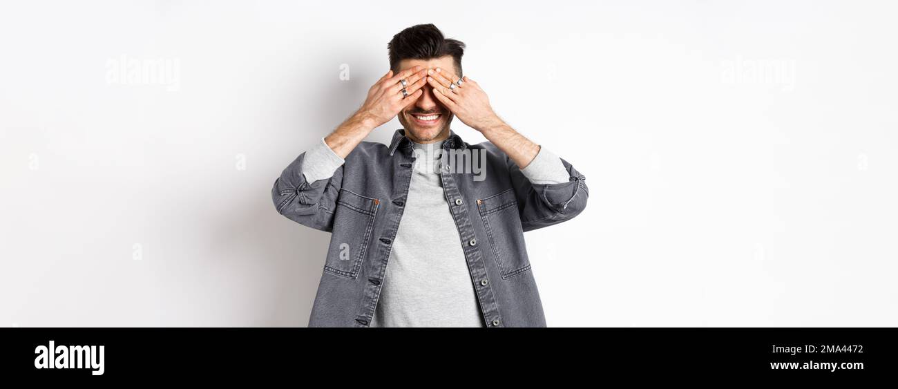 Happy smiling guy waiting with closed eyes for surprise, standing ...
