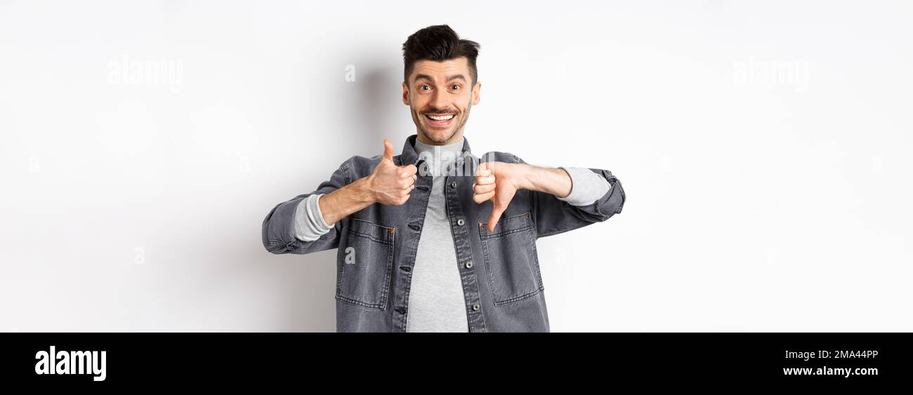 Happy smiling guy showing average gesture, thumbs down up, cant decide ...