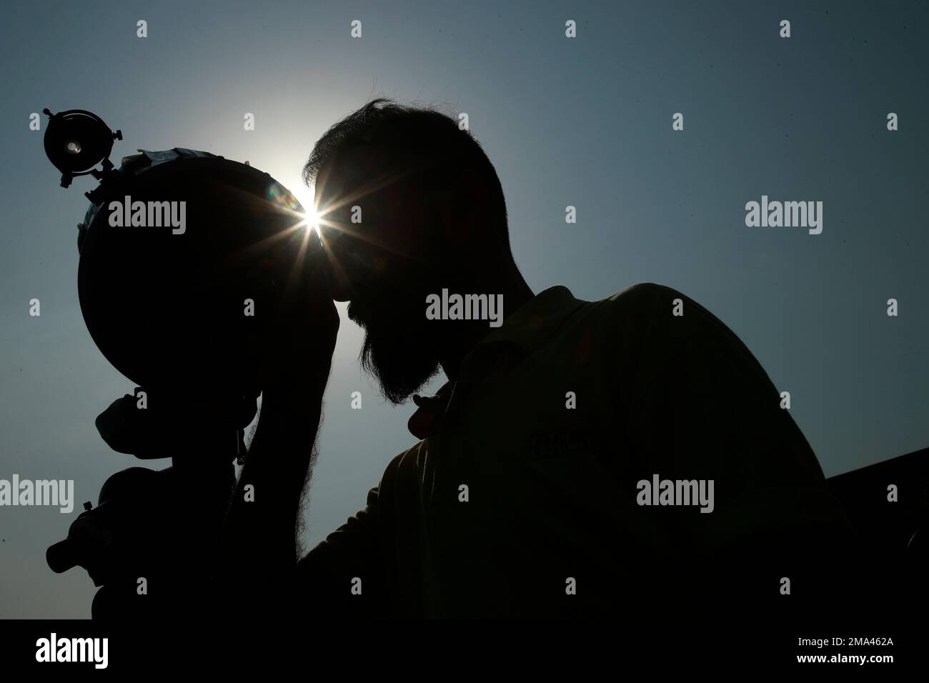 A man watches the solar eclipse in Baghdad, Iraq, Tuesday, Oct. 25 ...