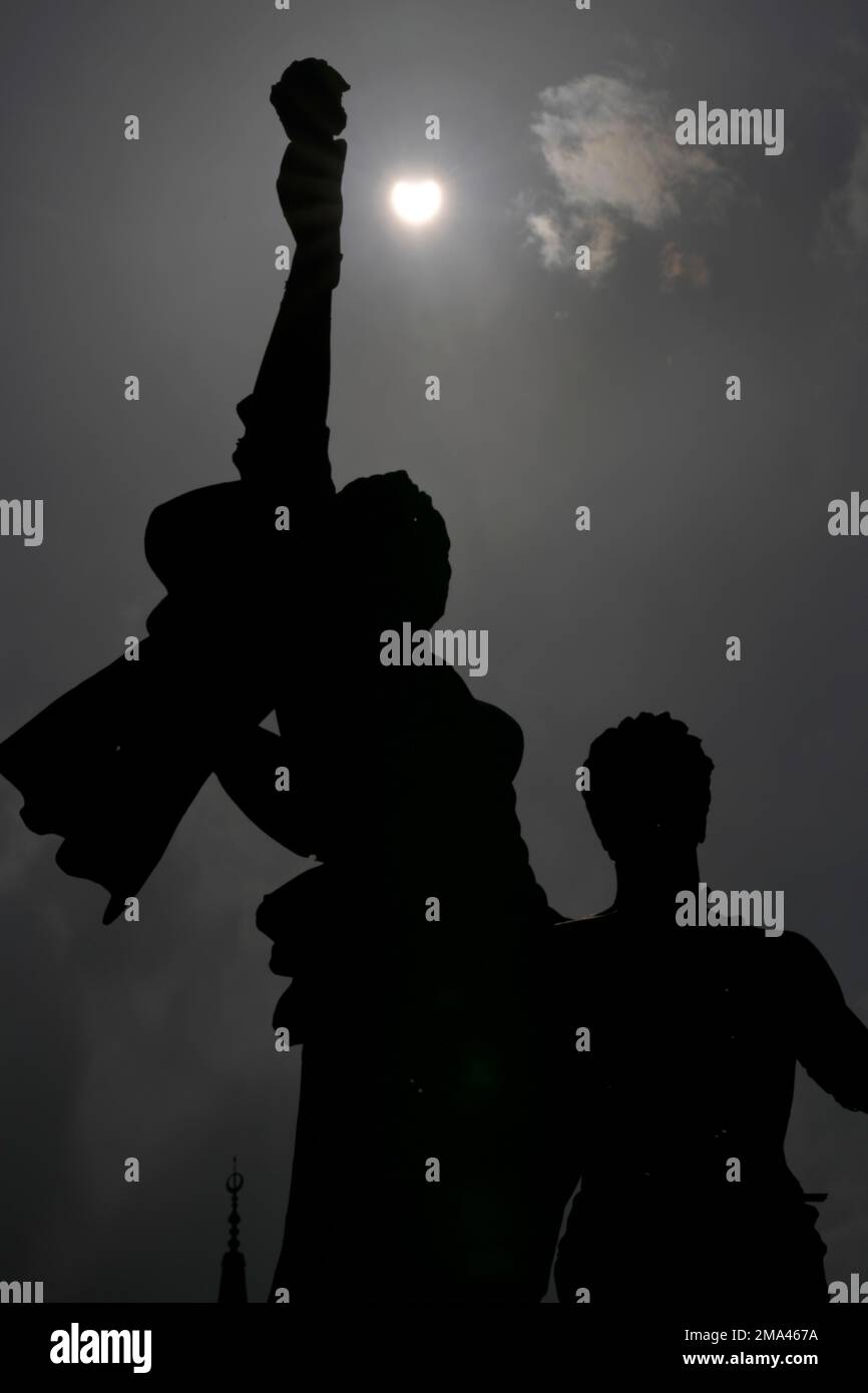 A partial solar eclipse is seen behind the Statue of Martyrs, in ...