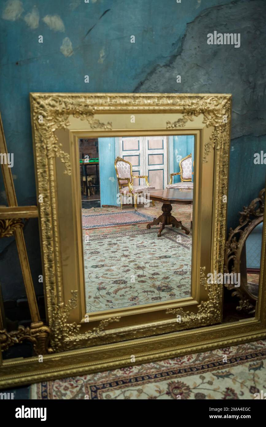 Reflection of a shabby 19th century parlour room in a gilded mirror ...