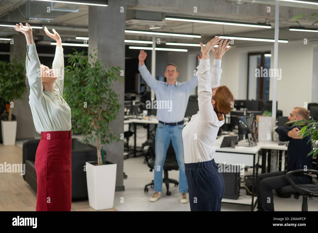 Four office workers warm up during a break. Employees do fitness ...