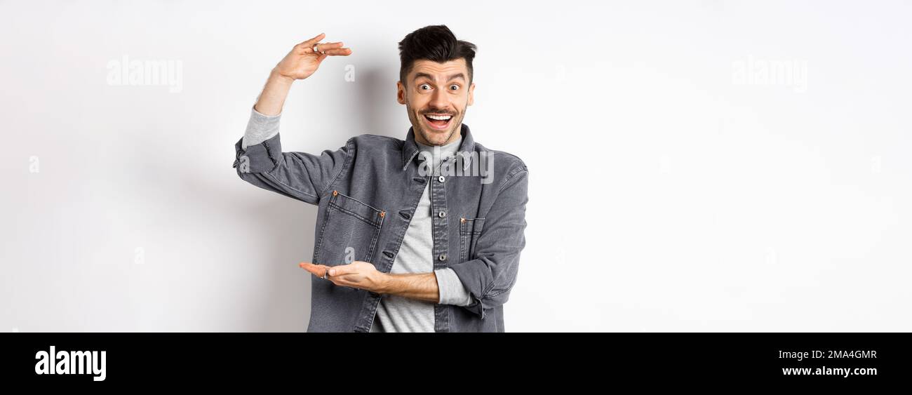Cheerful guy smiling and showing big size, showing large thing and ...