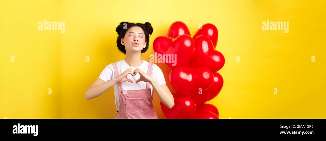 Romantic girl close eyes and pucker lips for kiss, showing I love you ...
