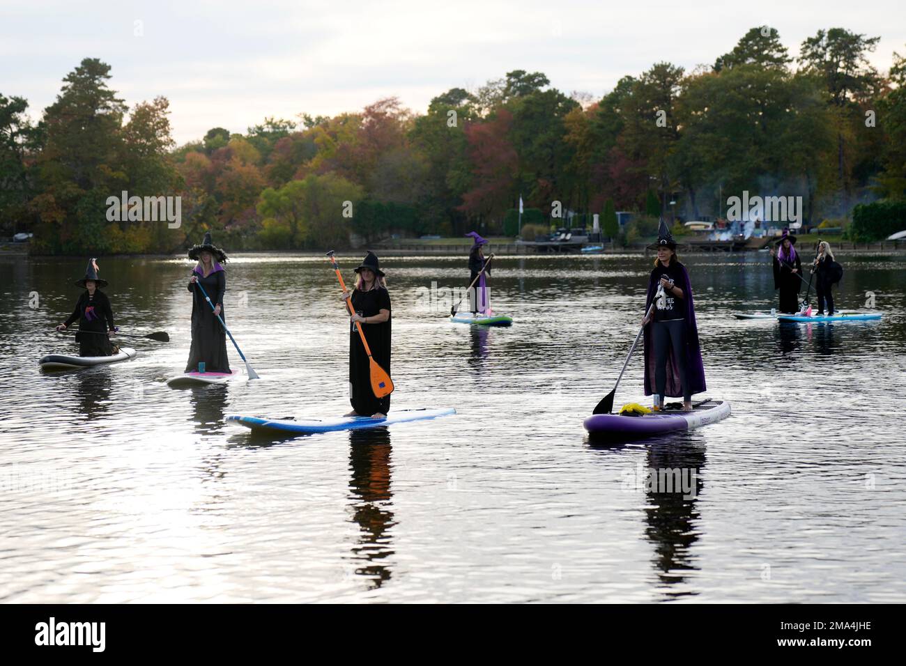 Participants dressed as witches ride paddle boards during the Medford ...