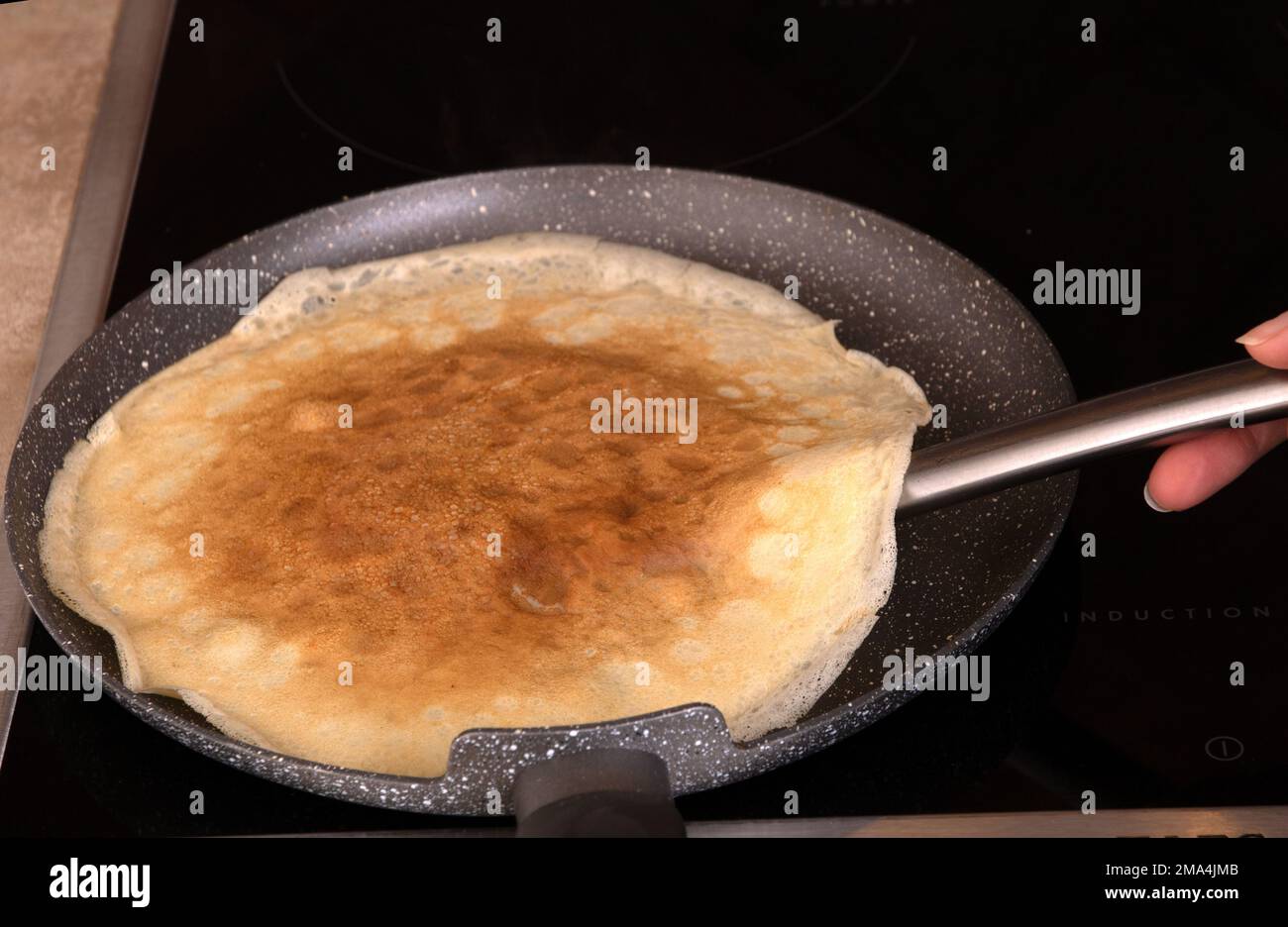 photo of a thin pancake frying on a griddle on the stove Stock Photo ...