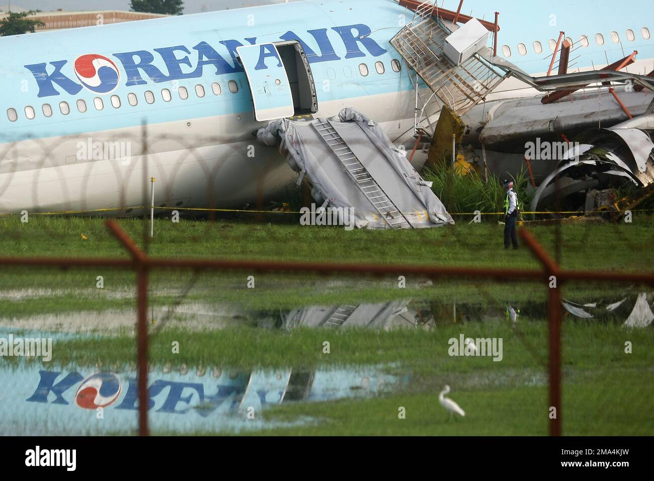 A security guard walks beside a damaged Korean Air plane on Monday Oct. 24, 2022 after it ...