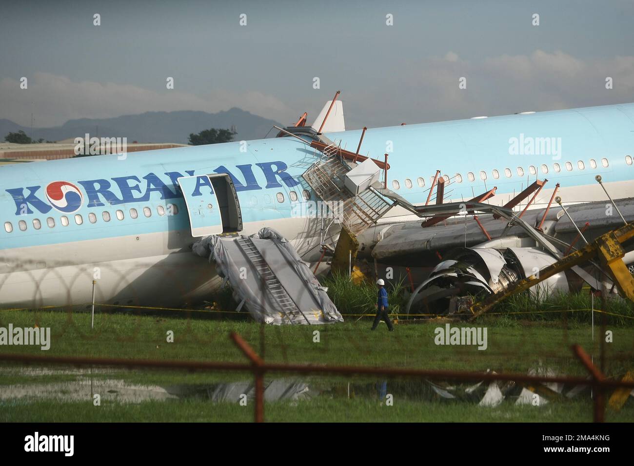 A man walks beside a damaged Korean Air plane after it overshot the runway at the Mactan-Cebu ...