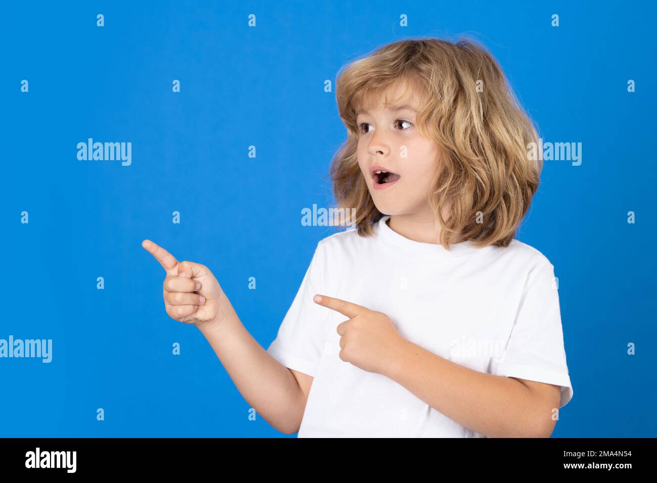 Excited child pointing finger on isolated studio background. Kid ...