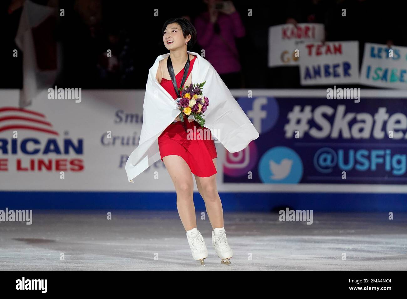 Kaori Sakamoto, of Japan, celebrates with flowers and the flag of Japan ...