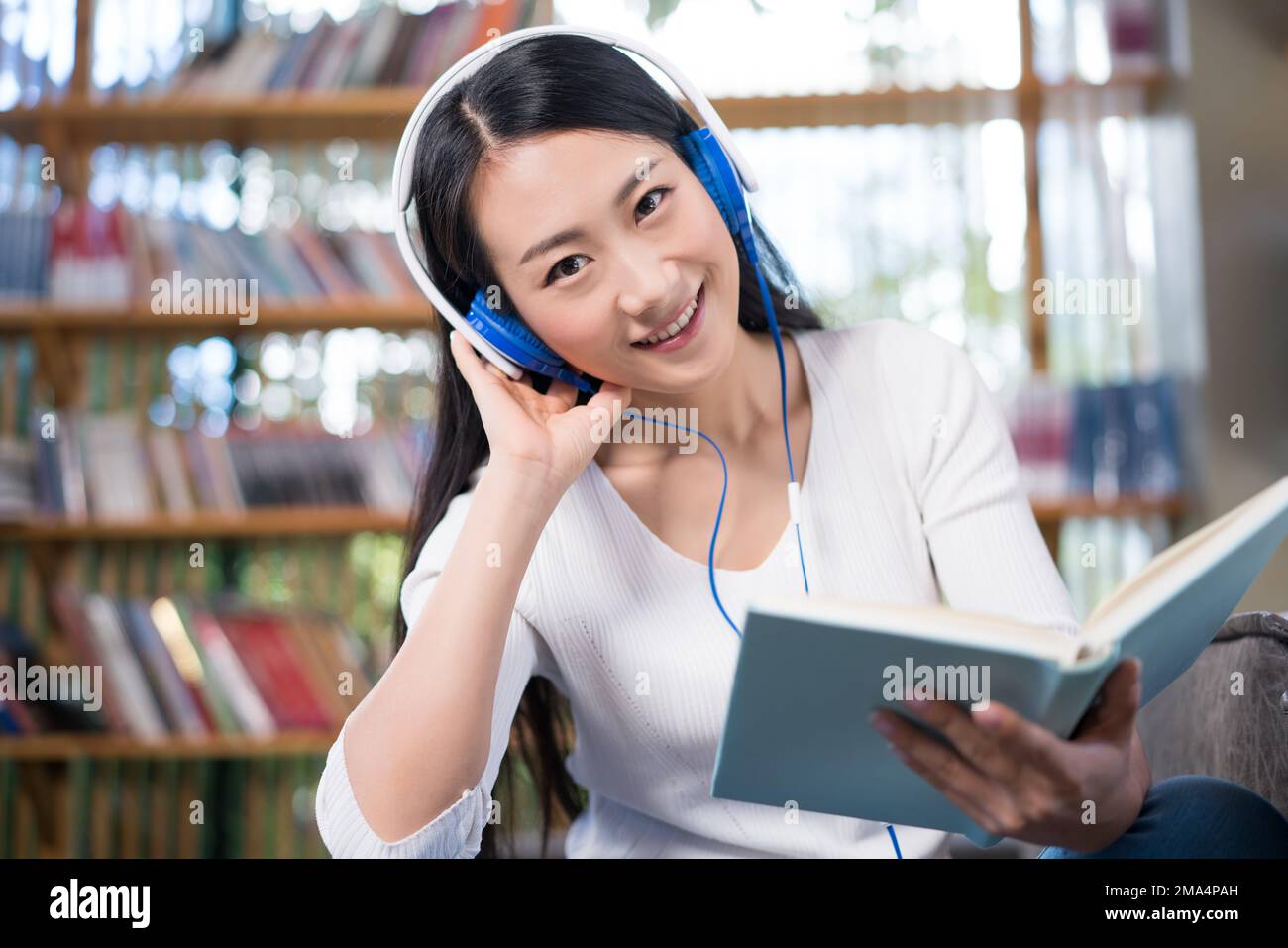 The young woman reading a book to listen to music Stock Photo - Alamy