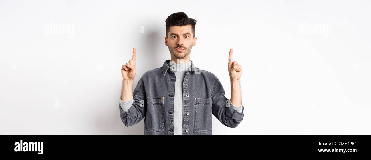 Serious caucasian guy with moustache, pointing fingers up at empty ...
