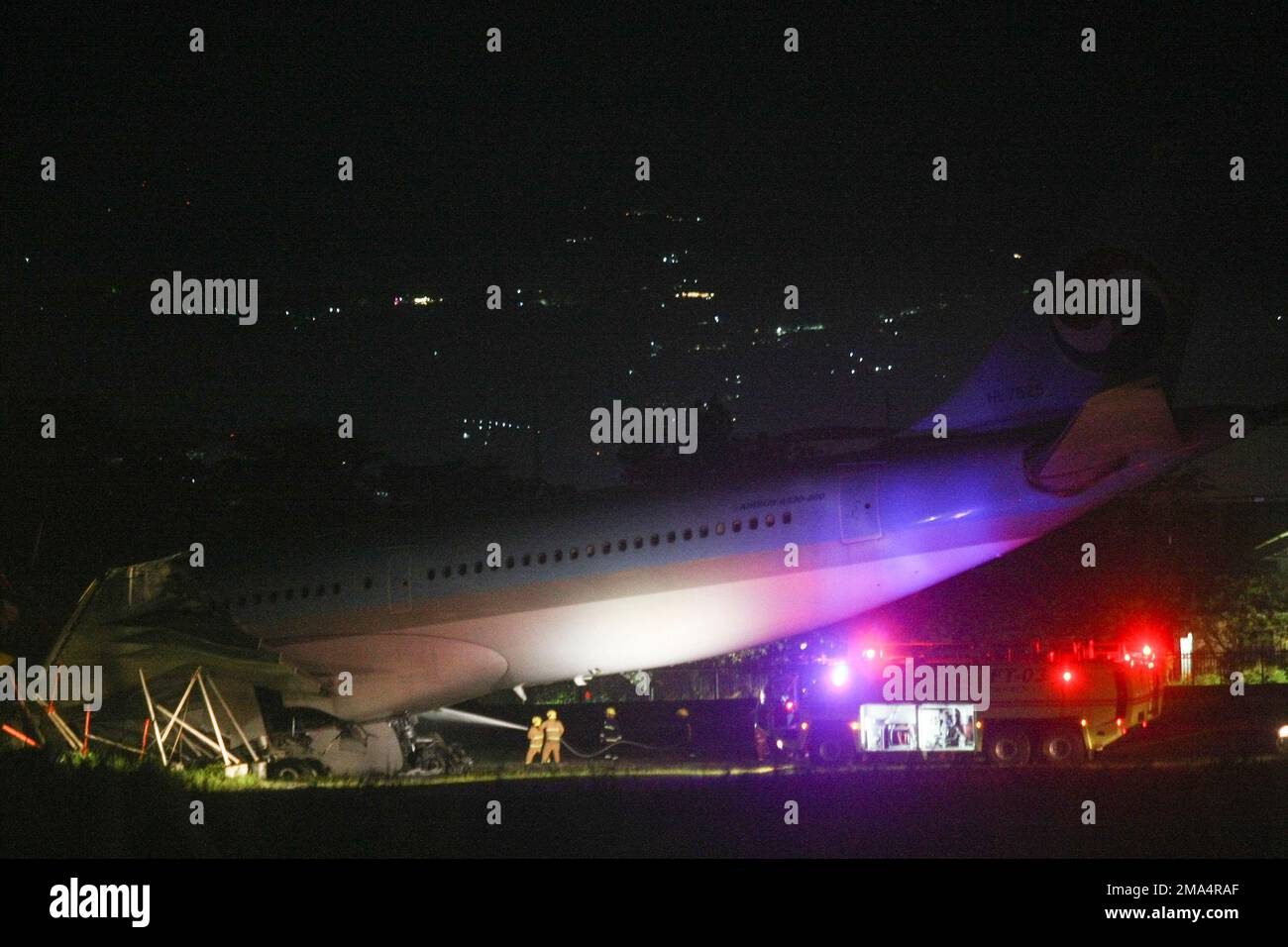 Firefighters train their hoses on a Korean Air Lines Co. plane after it overshot the runway at ...