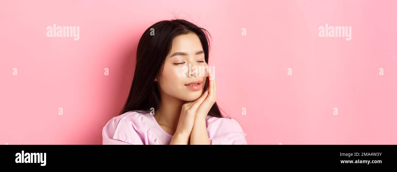 Tender and romantic girl gently touching face, close eyes and smiling ...
