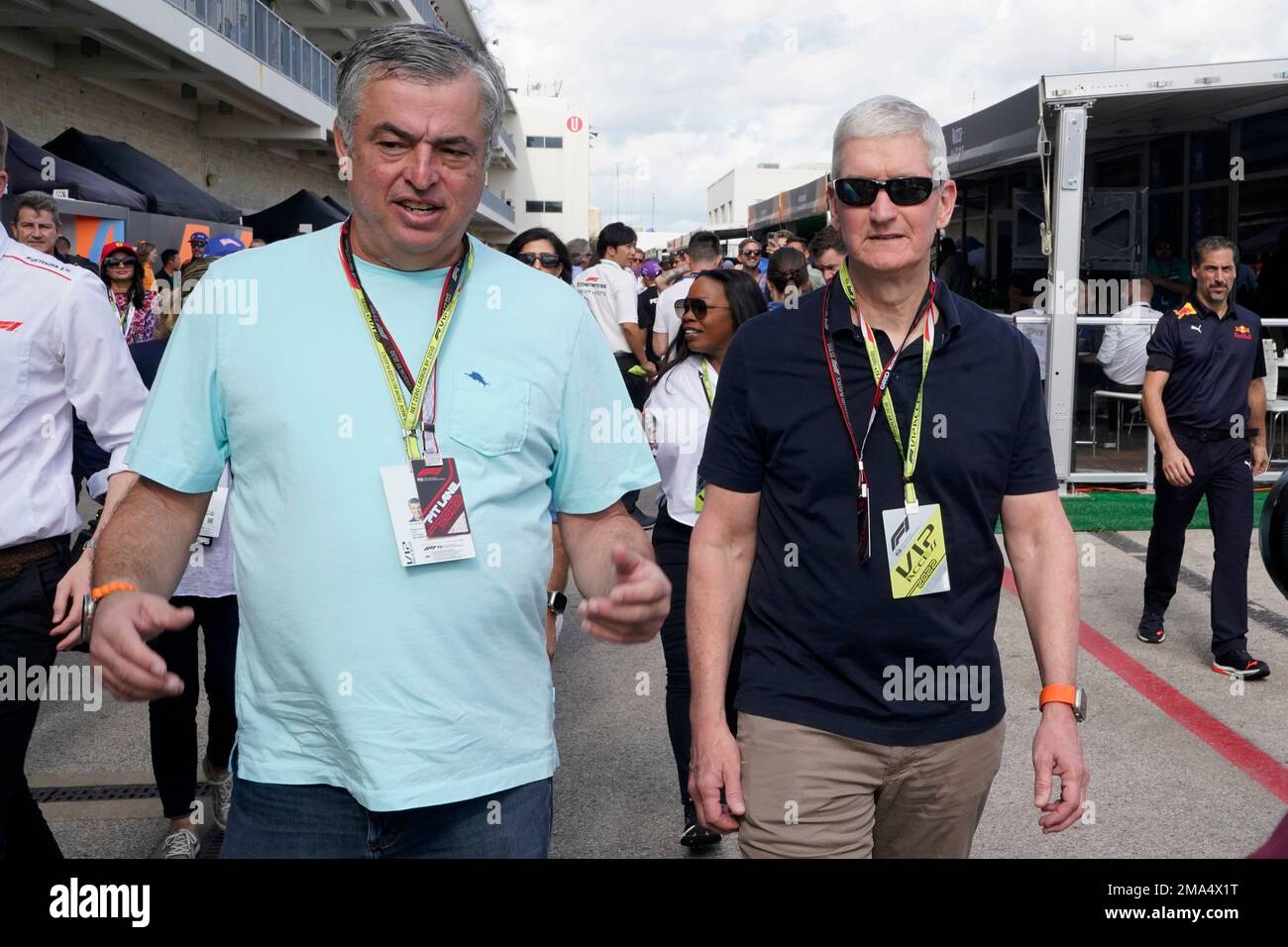 Apple CEO Tim Cook, right, walks through the paddock before the Formula ...
