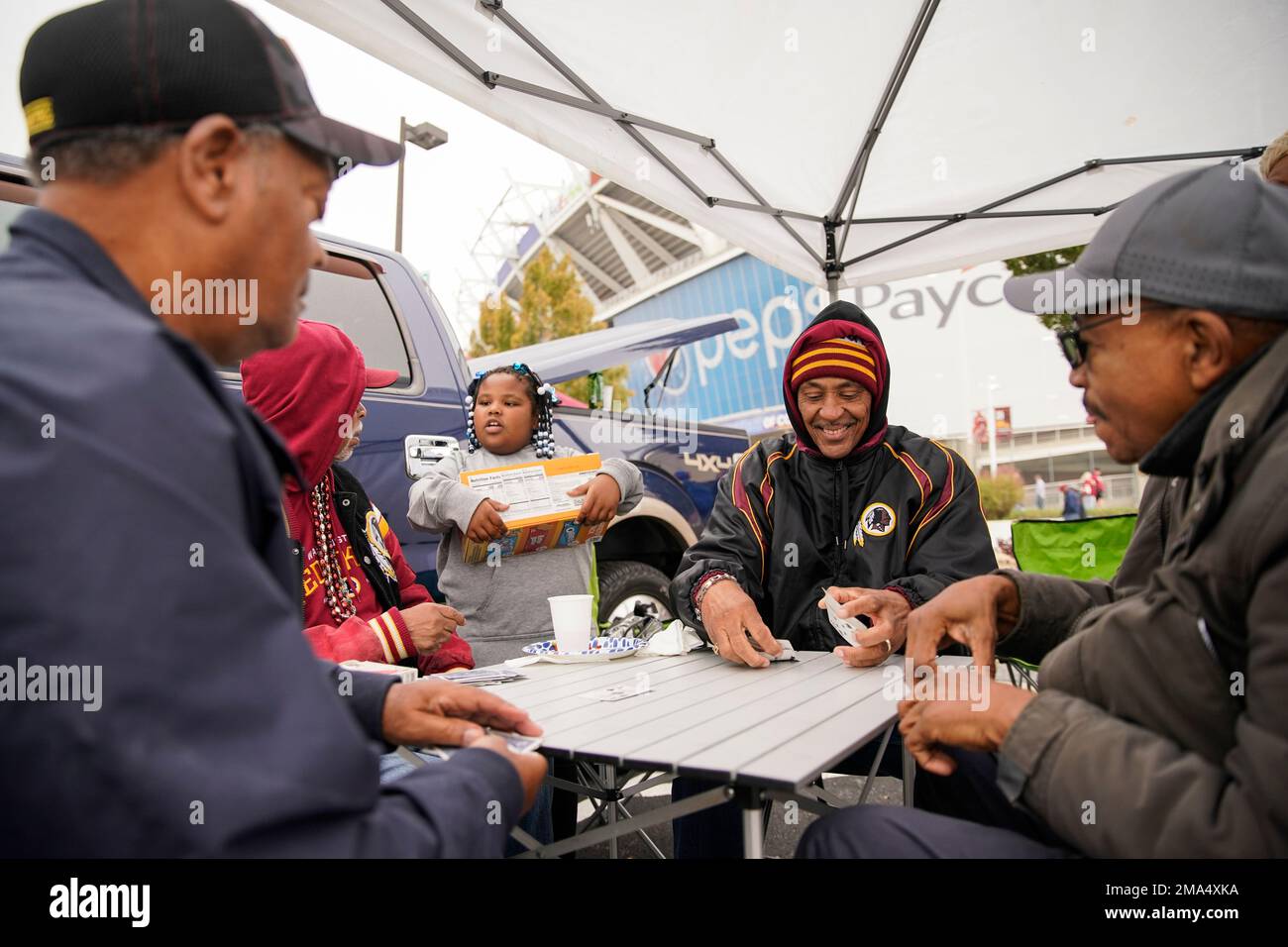 Fans play cards as they tailgate in the parking lot around the stadium ...