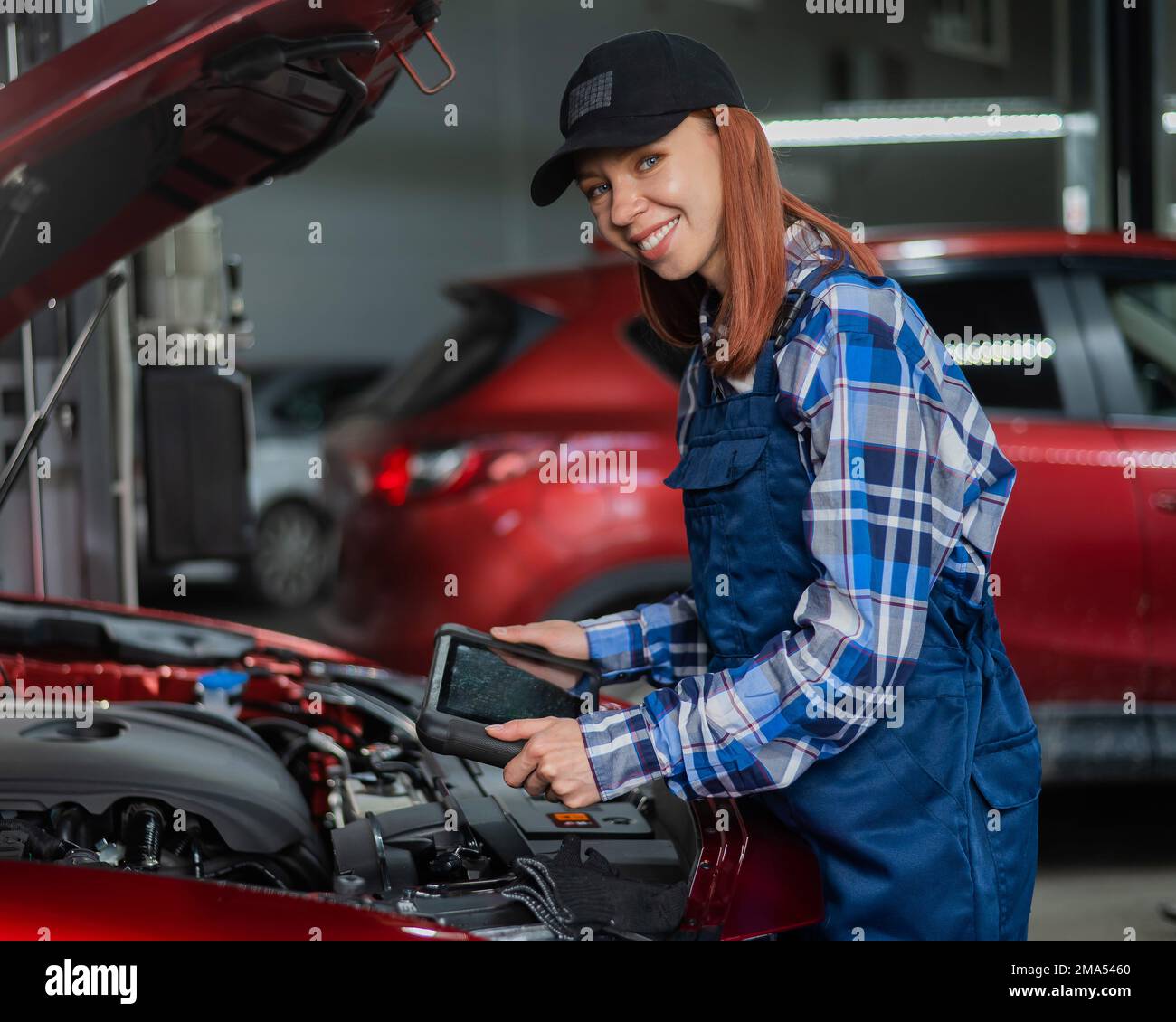 Caucasian female auto mechanic uses a special computer to diagnose ...