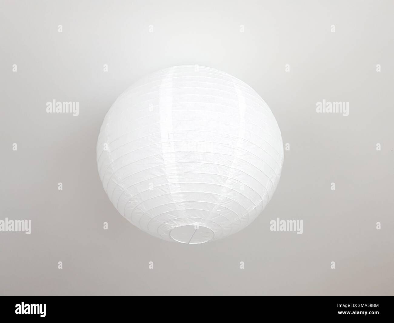 White round ceiling lamp on a white ceiling. Paper round lampshade ...