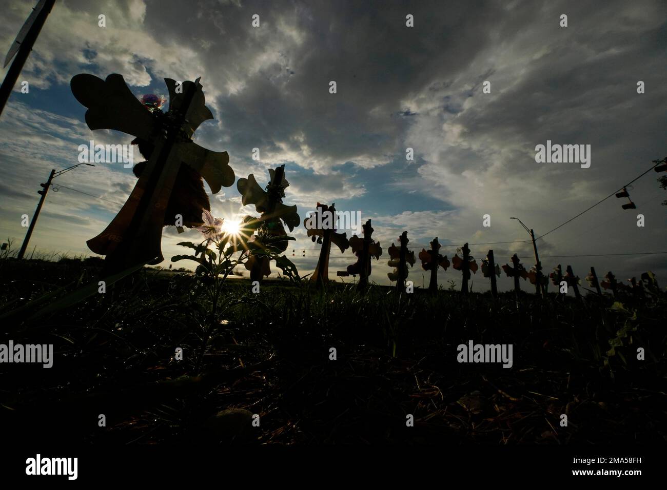 FILE - Vehicles pass crosses placed to honor the victims of the ...