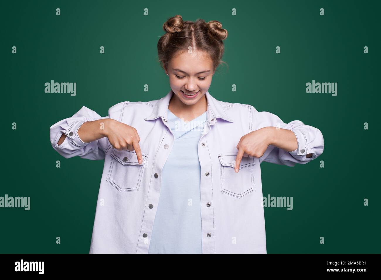 Portrait of young woman pointing fingers down and smiling, showing ...
