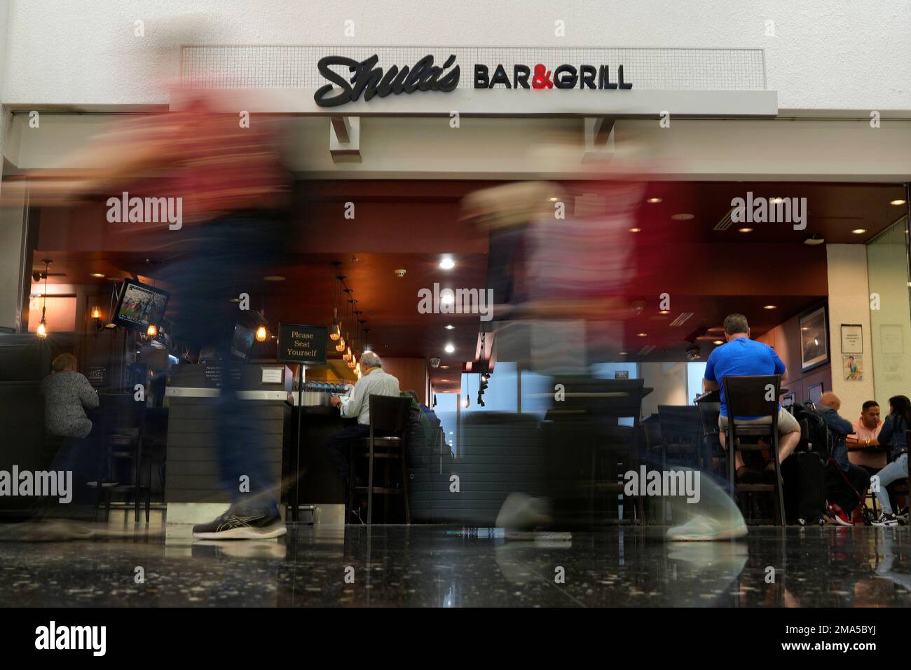 Travelers walk past Shula's Bar & Grill, named for former Miami ...
